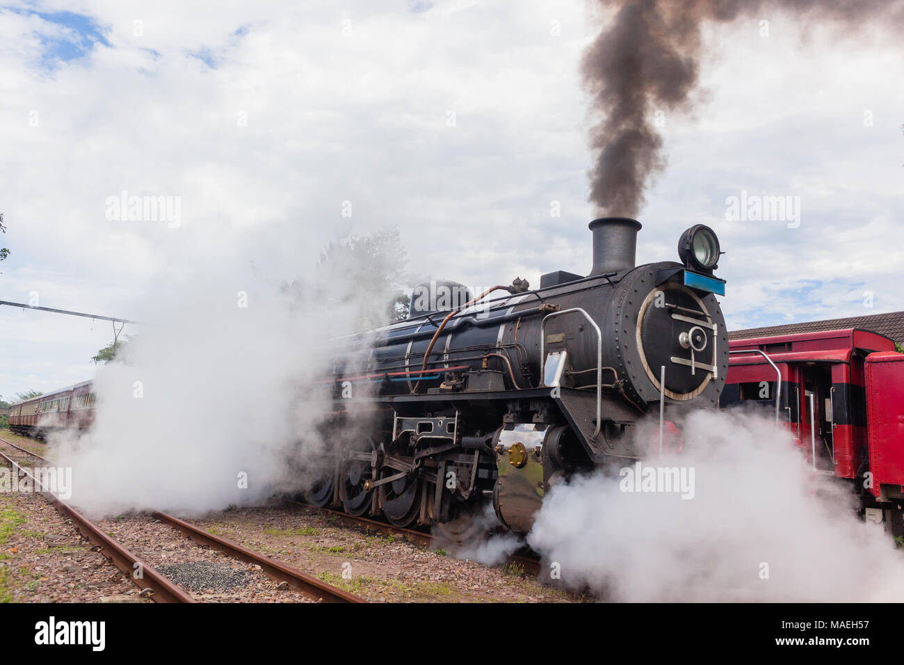 Steam train locomotive with passenger coaches closeup exhuasts pulls ...
