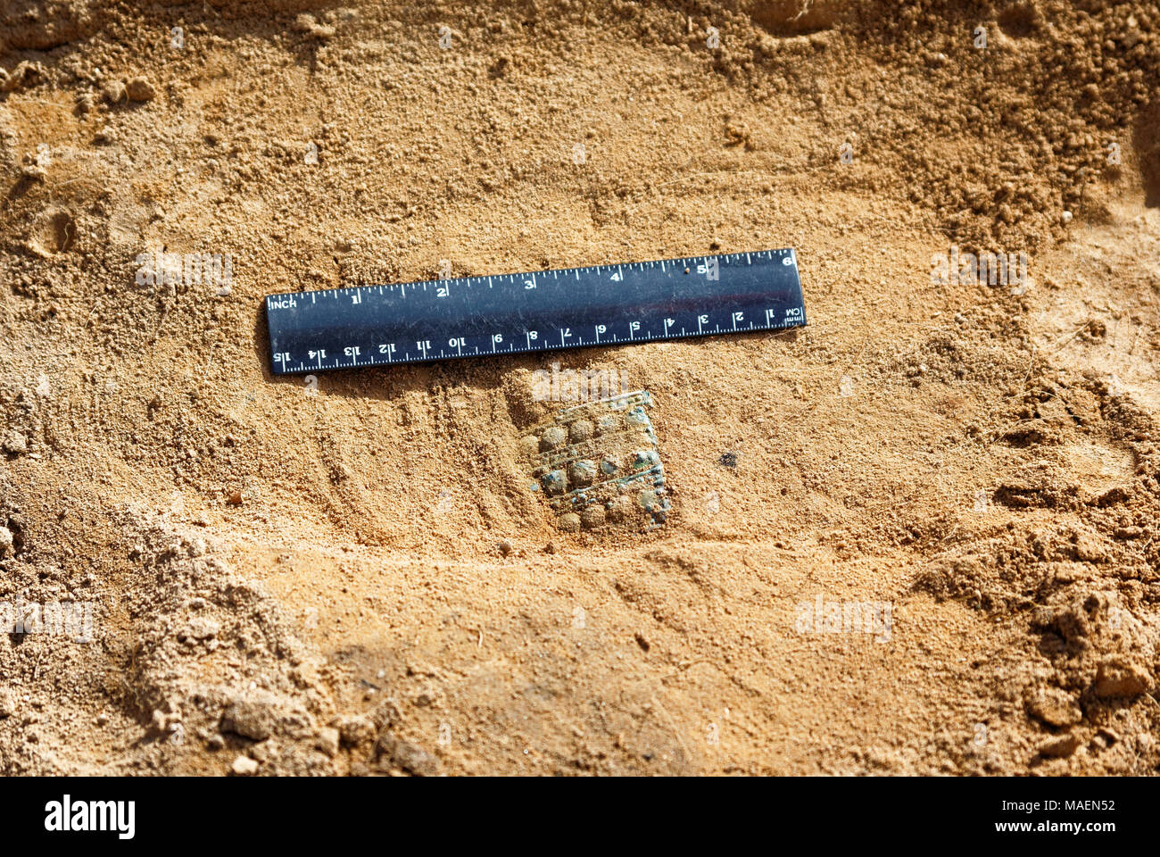 An ornamental bronze plate in comparison with the scale of the ruler.A ...