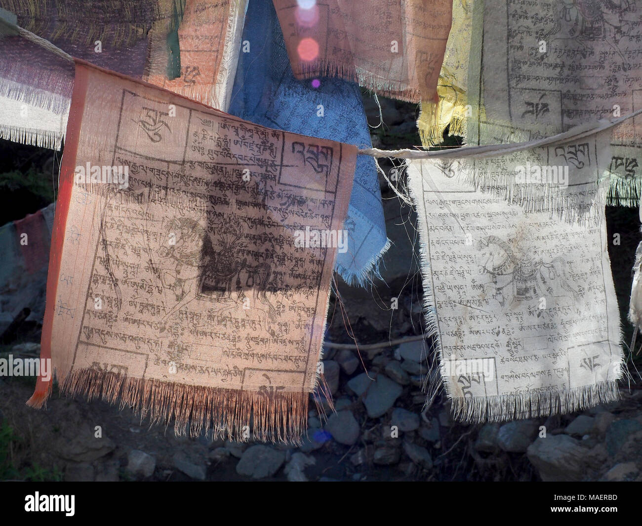 Buddhist old prayer flags on ropes in the sun on a dark background ...