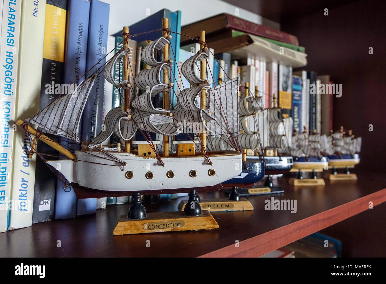 Line of four small model sailing ships on book shelf, Antalya, Turkey ...