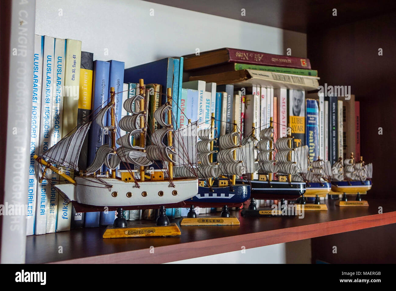Line of four small model sailing ships on book shelf, Antalya, Turkey ...
