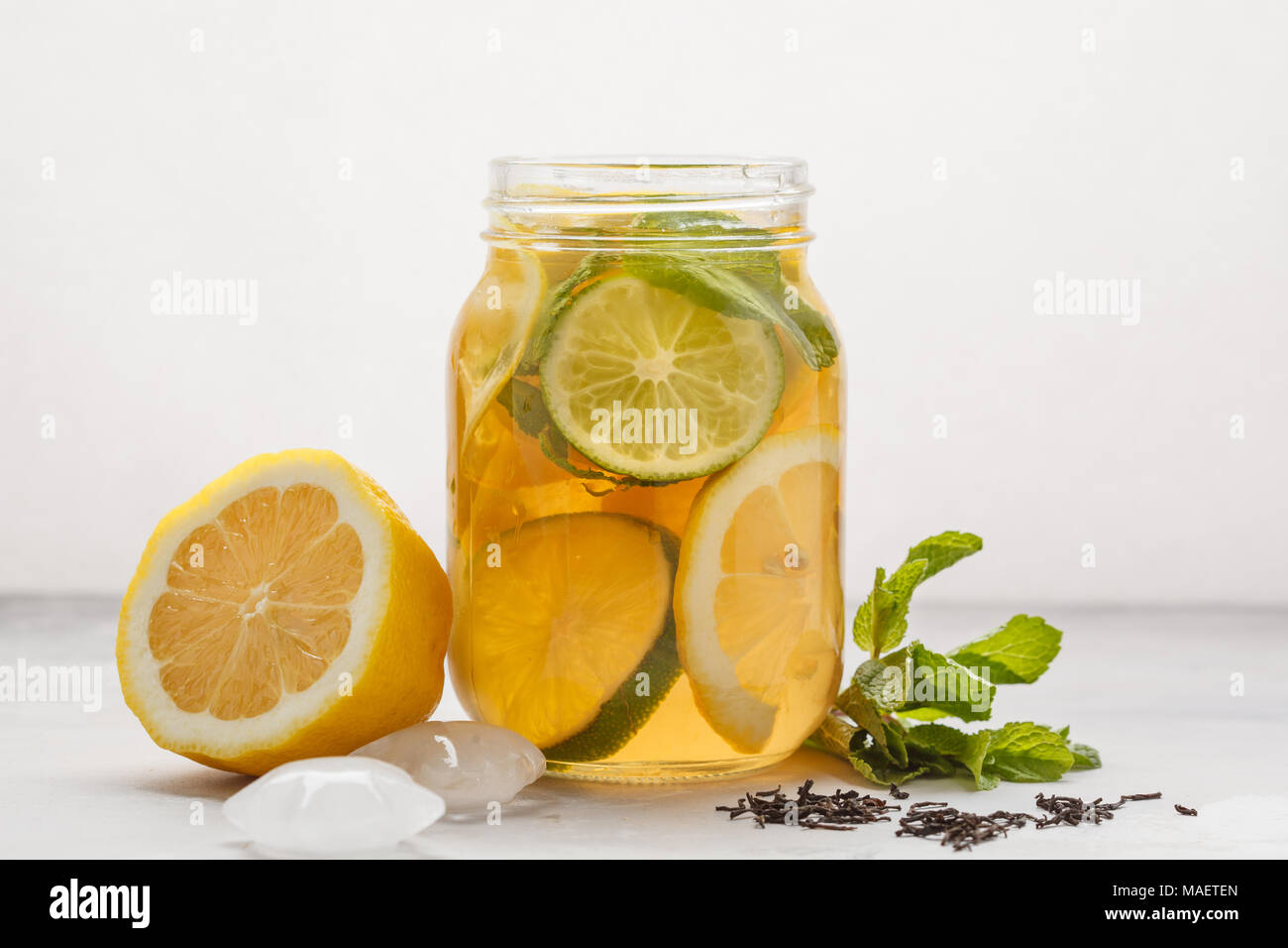 Lemon lime ice tea with mint in glass jar, white background, copy space ...
