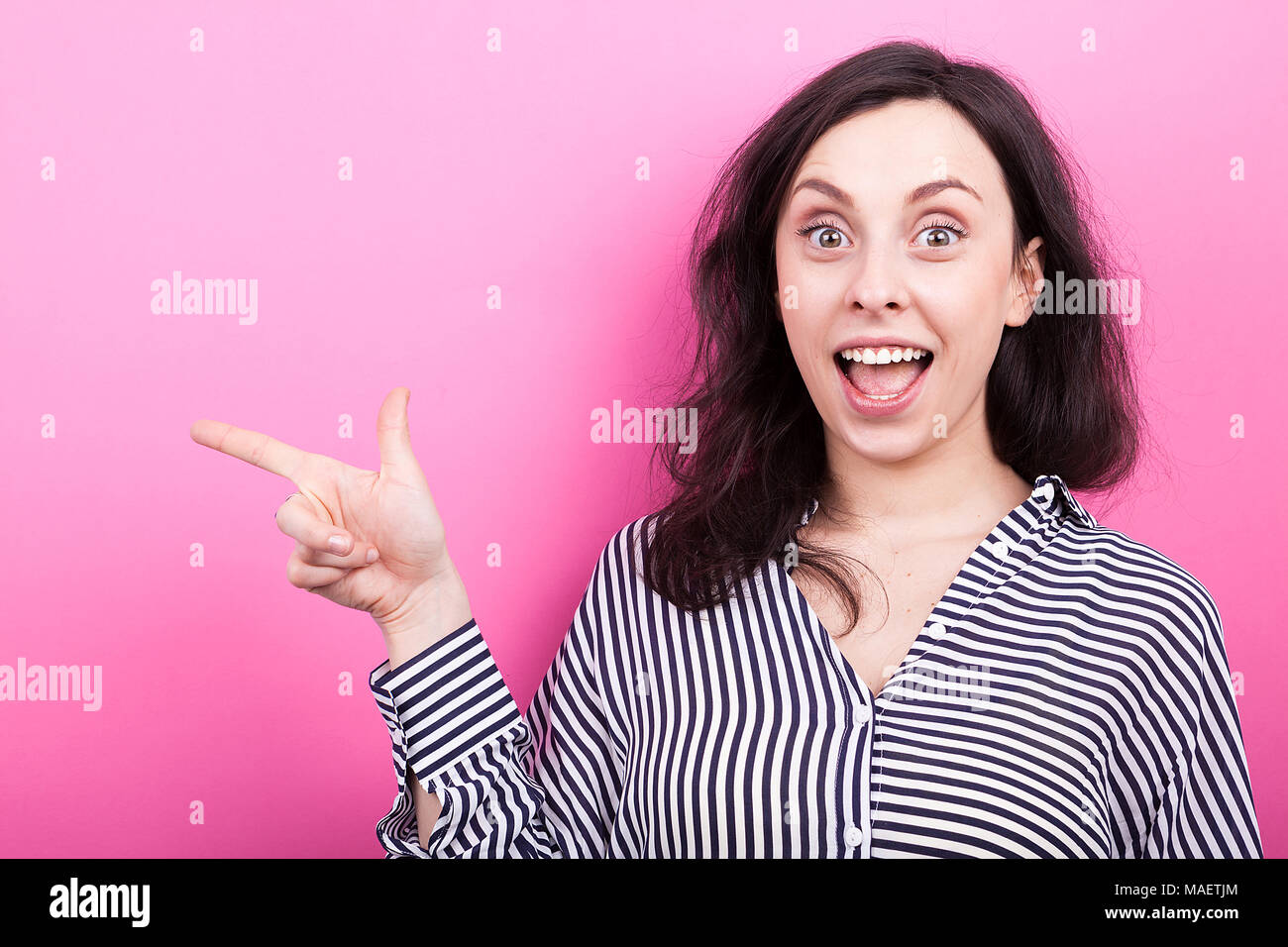 Surprised woman pointing to her right Stock Photo - Alamy