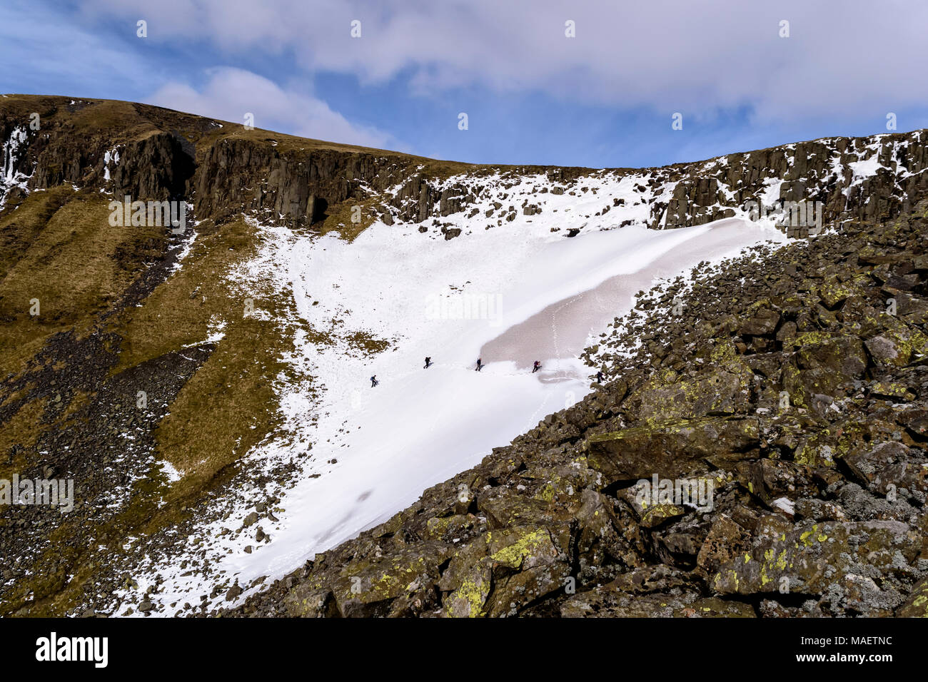Walkers traversing a snow field as they head up to the top of High Cup ...
