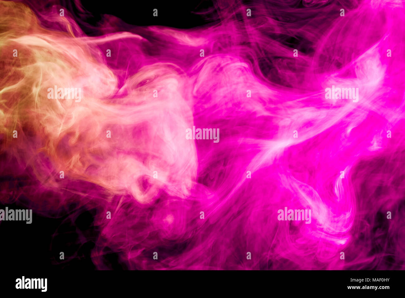 Thick colorful smoke of yellow and pink on a black isolated background ...