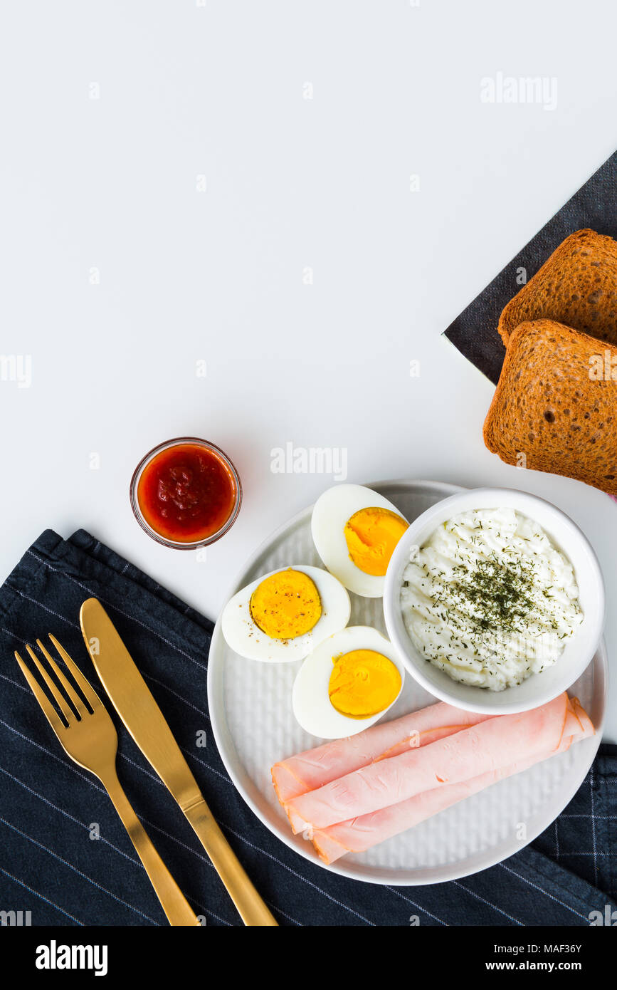 Breakfast, half boiled eggs, ham, toast and fresh cheese sprinkled with ...