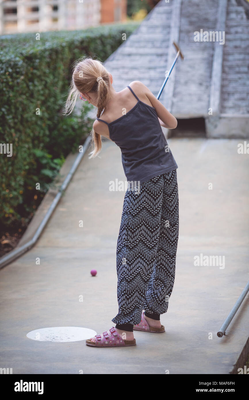 Happy little girl playing mini golf playing mini golf in a park at the ...
