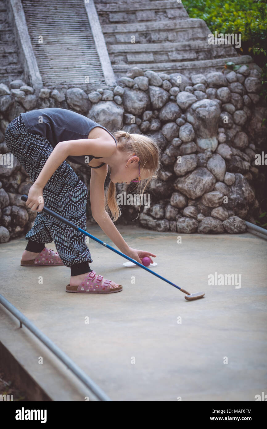 Happy little girl playing mini golf playing mini golf in a park at the ...
