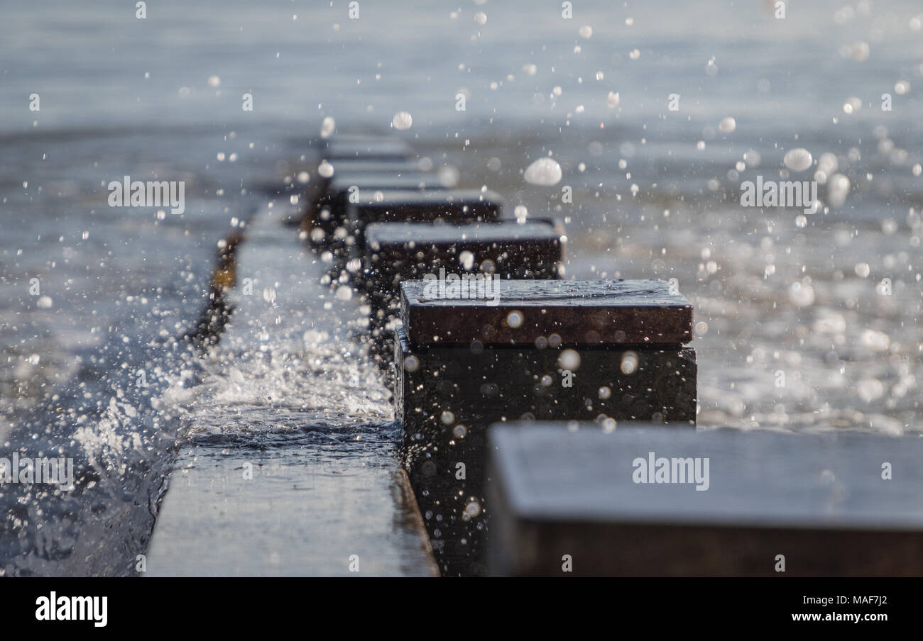 water from wave splashing over groyne in bay, Dorset UK Stock Photo - Alamy