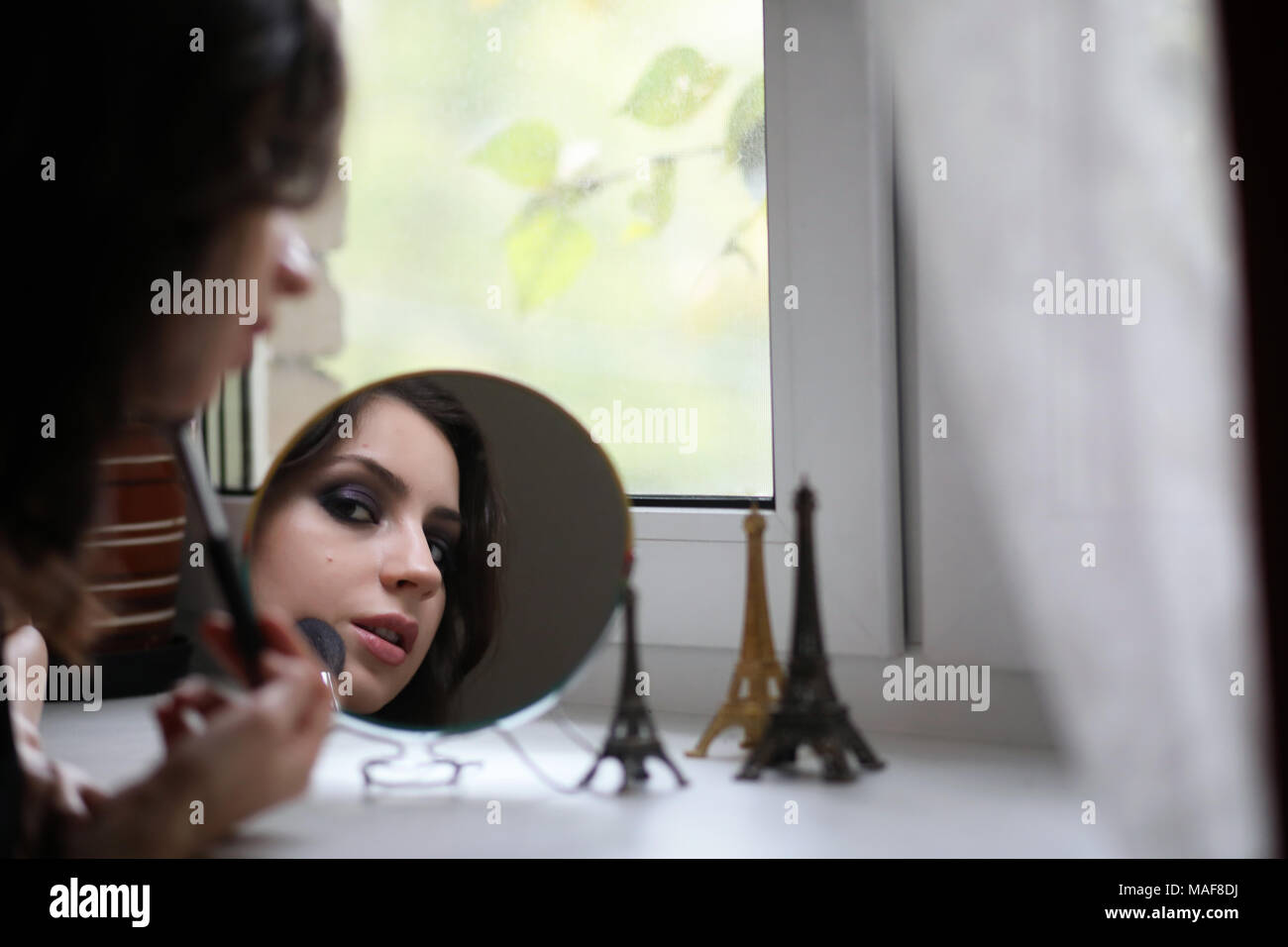 Beautiful girl doing makeup in front of a mirror Stock Photo - Alamy