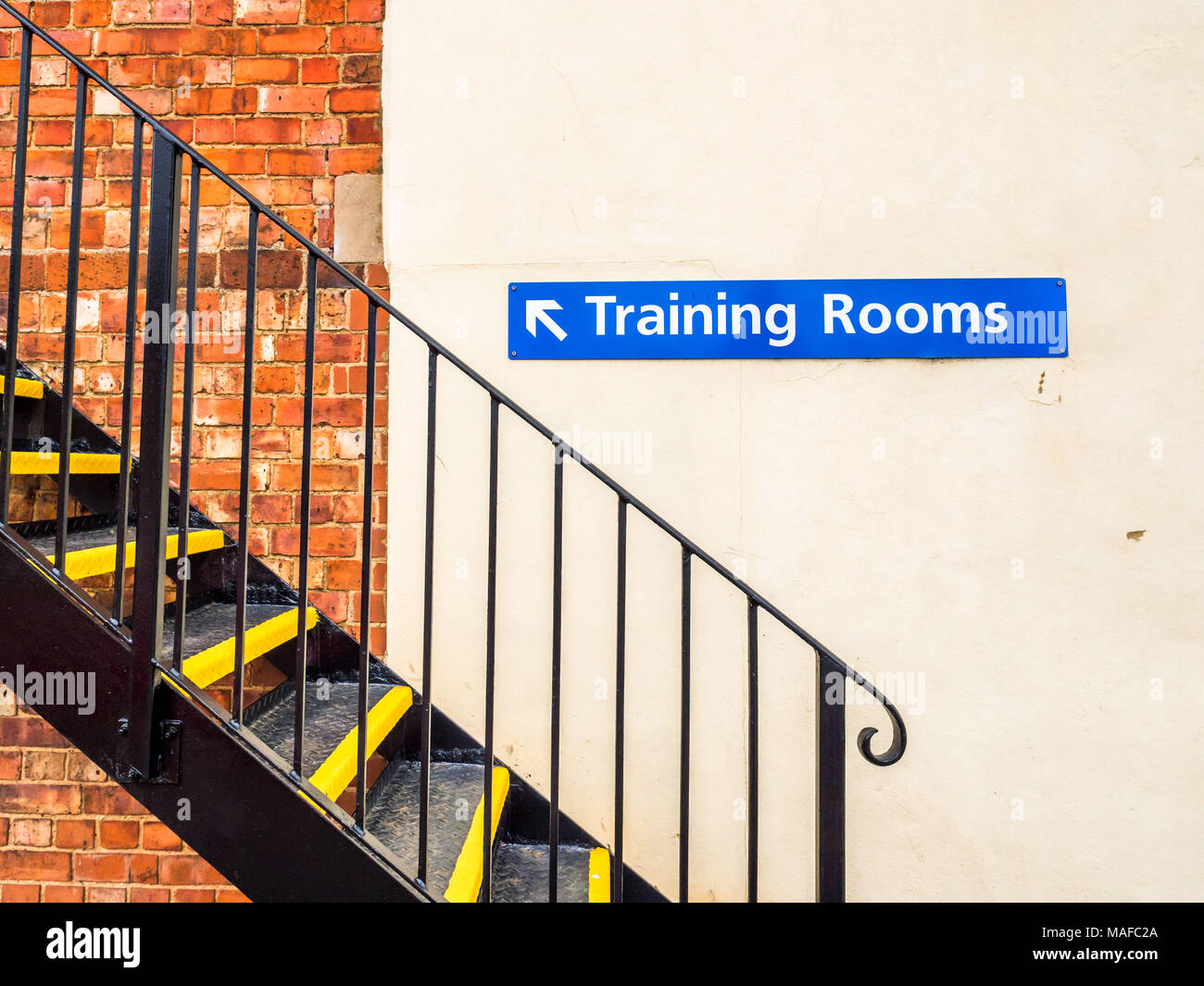 Side view of black metal stair with directional sign Training Rooms ...