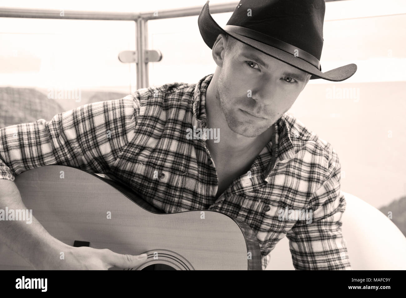 Handsome country and western cowboy singer wearing hat and playing ...