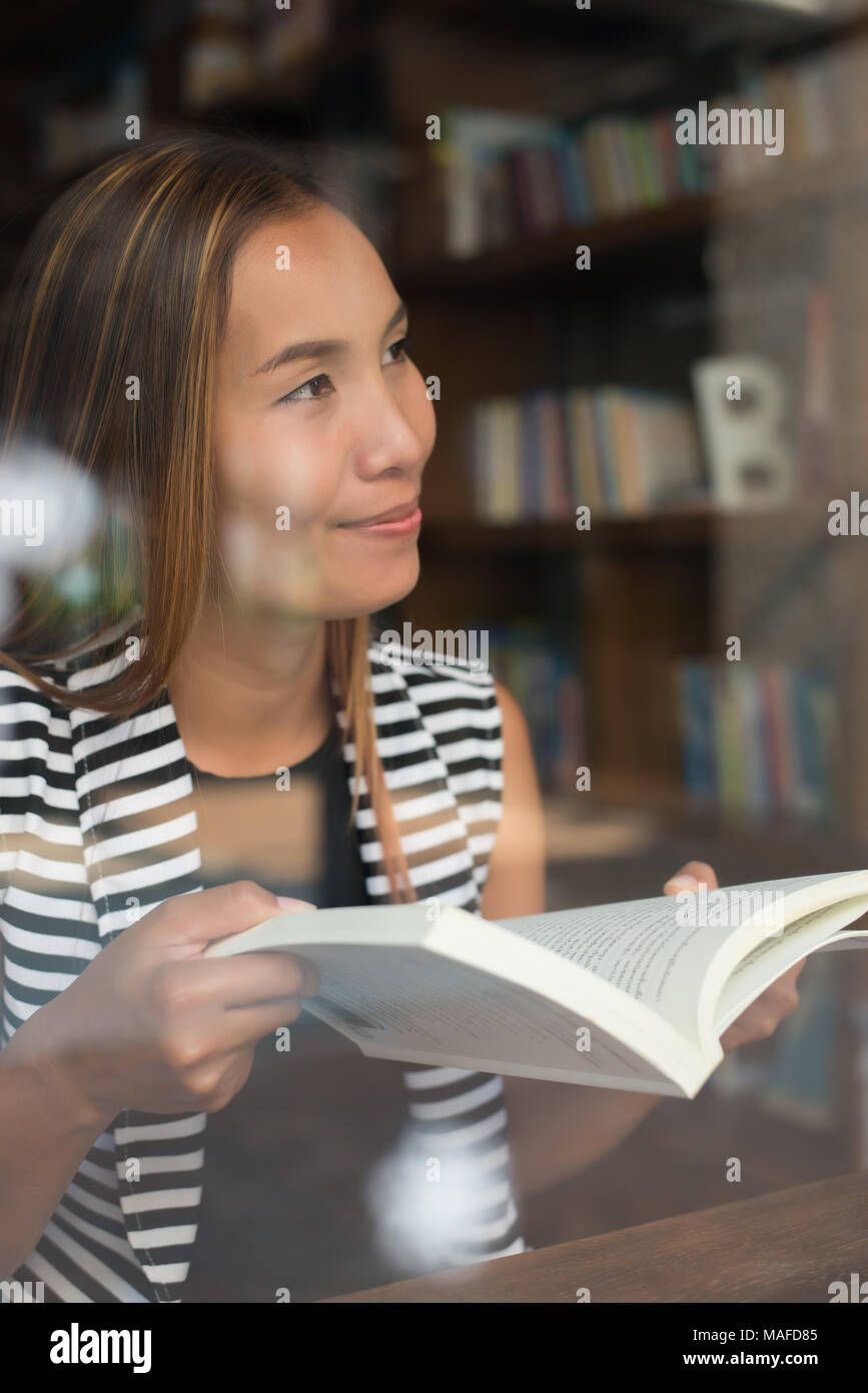 Asian woman reading a book in library Stock Photo - Alamy