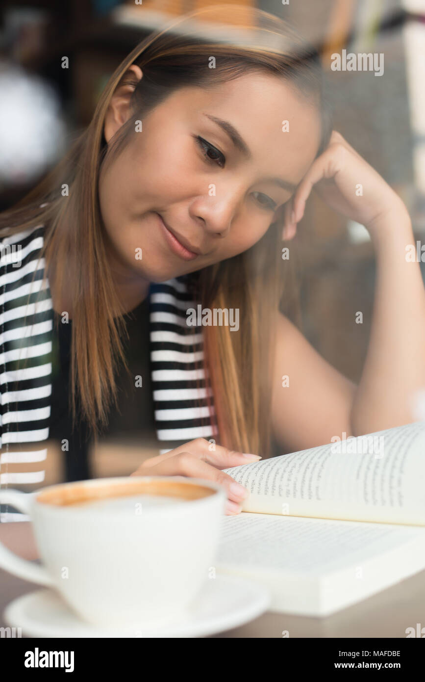 Asian woman relaxing and reading a book in the cafe. Women lifestyle ...