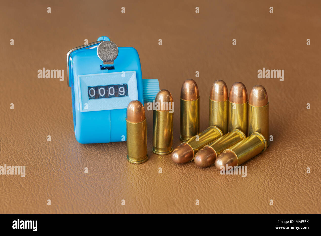 Hand tally counter and nine bullets on brown leather Stock Photo - Alamy