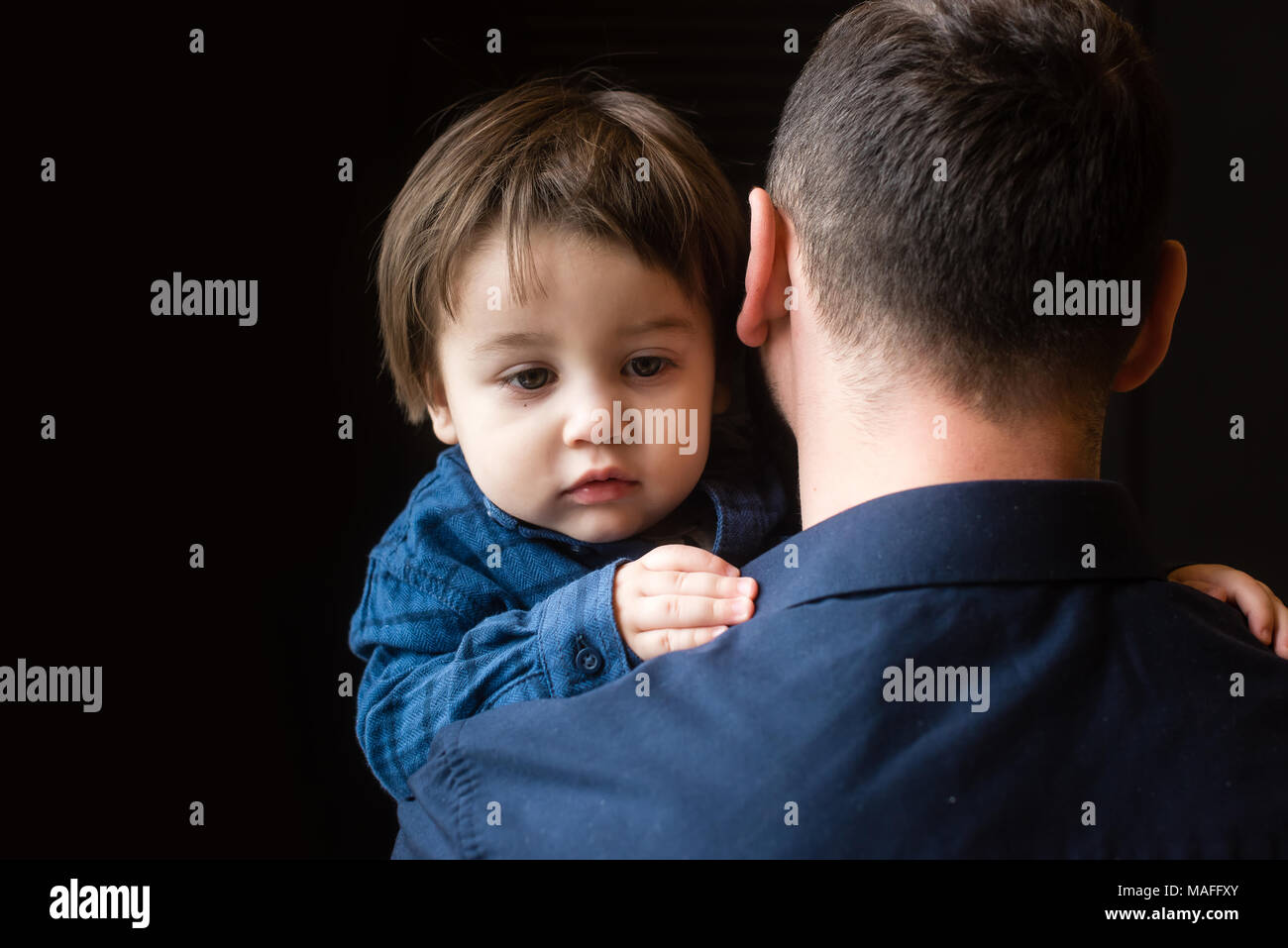 Studio portrait of small kid in man hugs at black background Stock ...