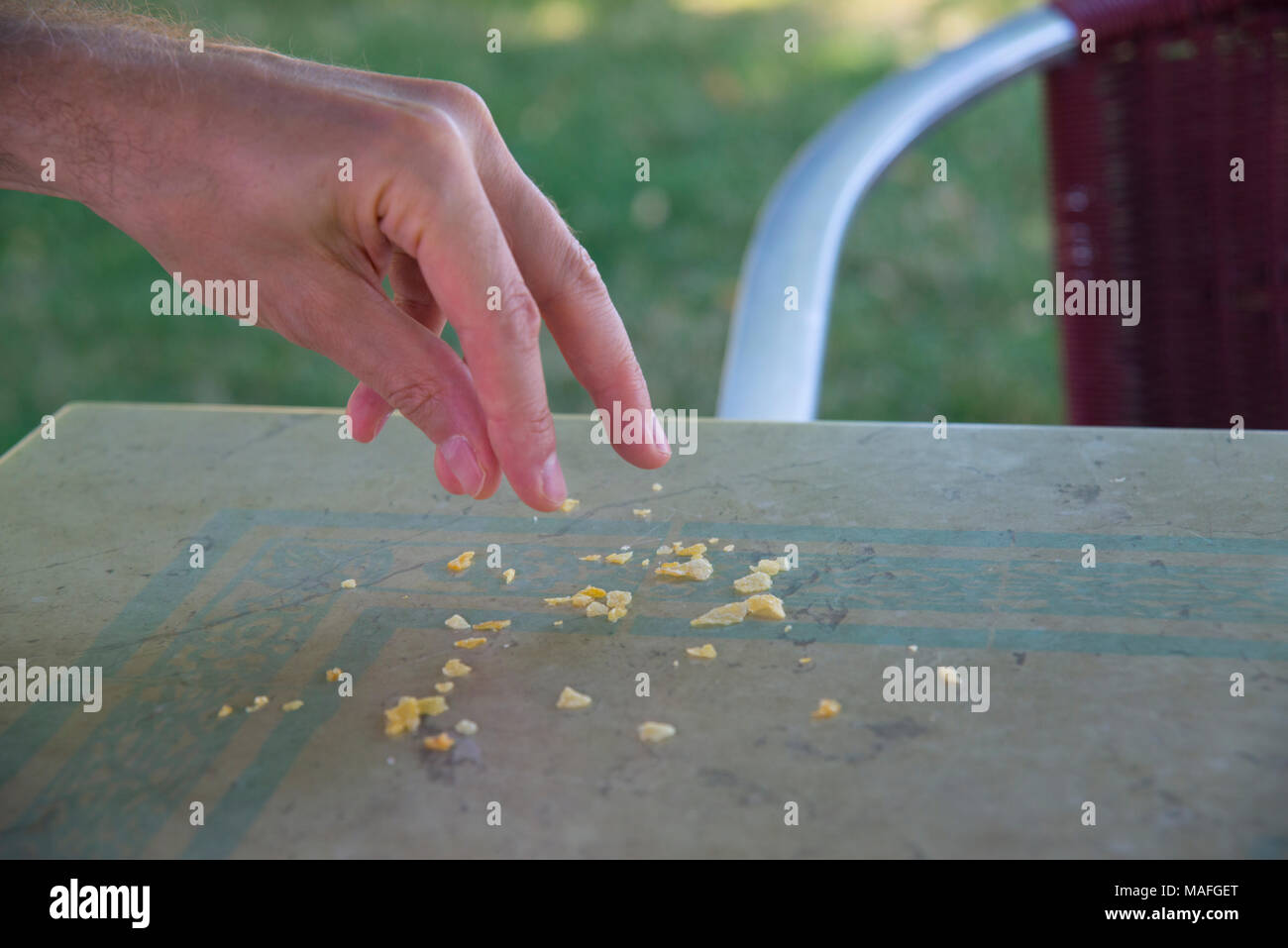 Man's hand dropping crumbs on a table Stock Photo - Alamy