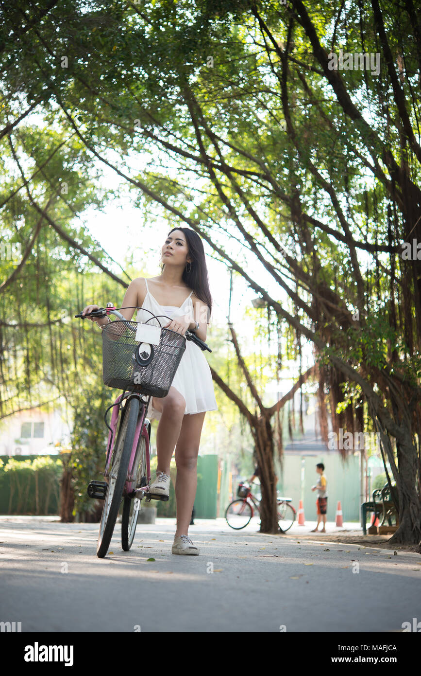 Young beautiful woman riding a bicycle in a park. Woman relaxing ...