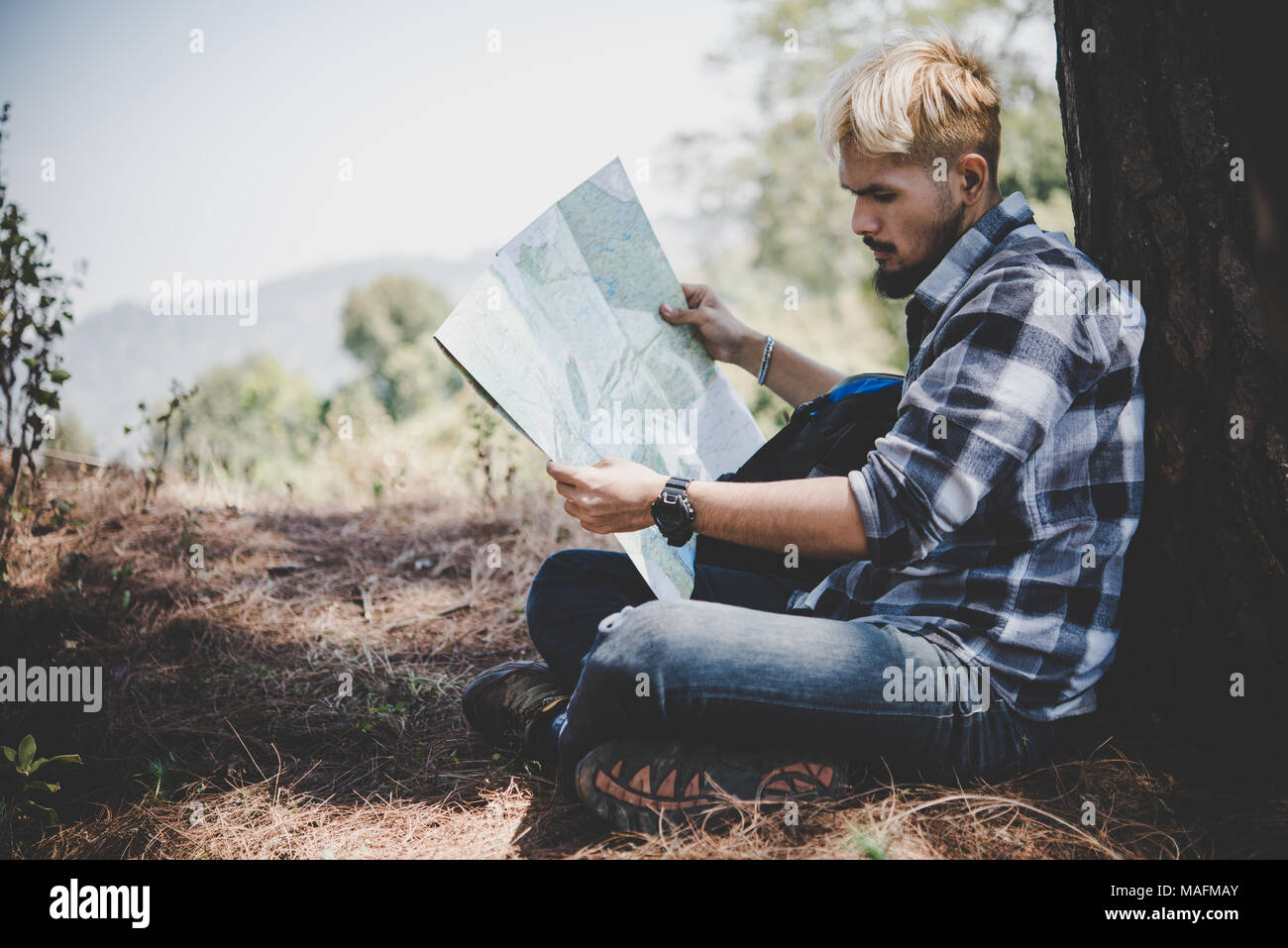 Hiker relaxing by tree looking at map, go adventure in mountain Stock ...