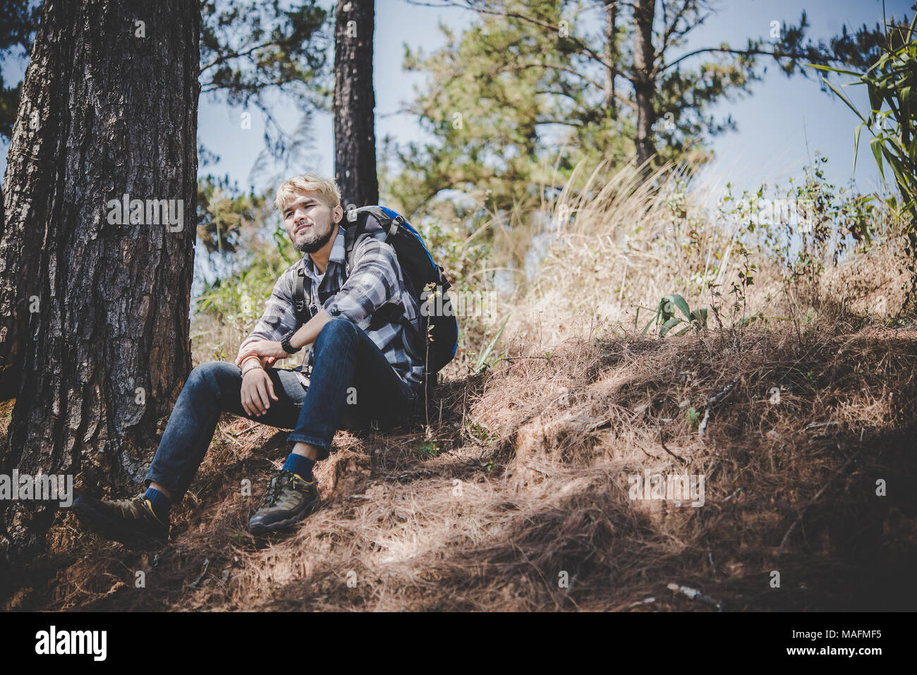 Young tired hiker with backpack sitting on the mountain top while ...