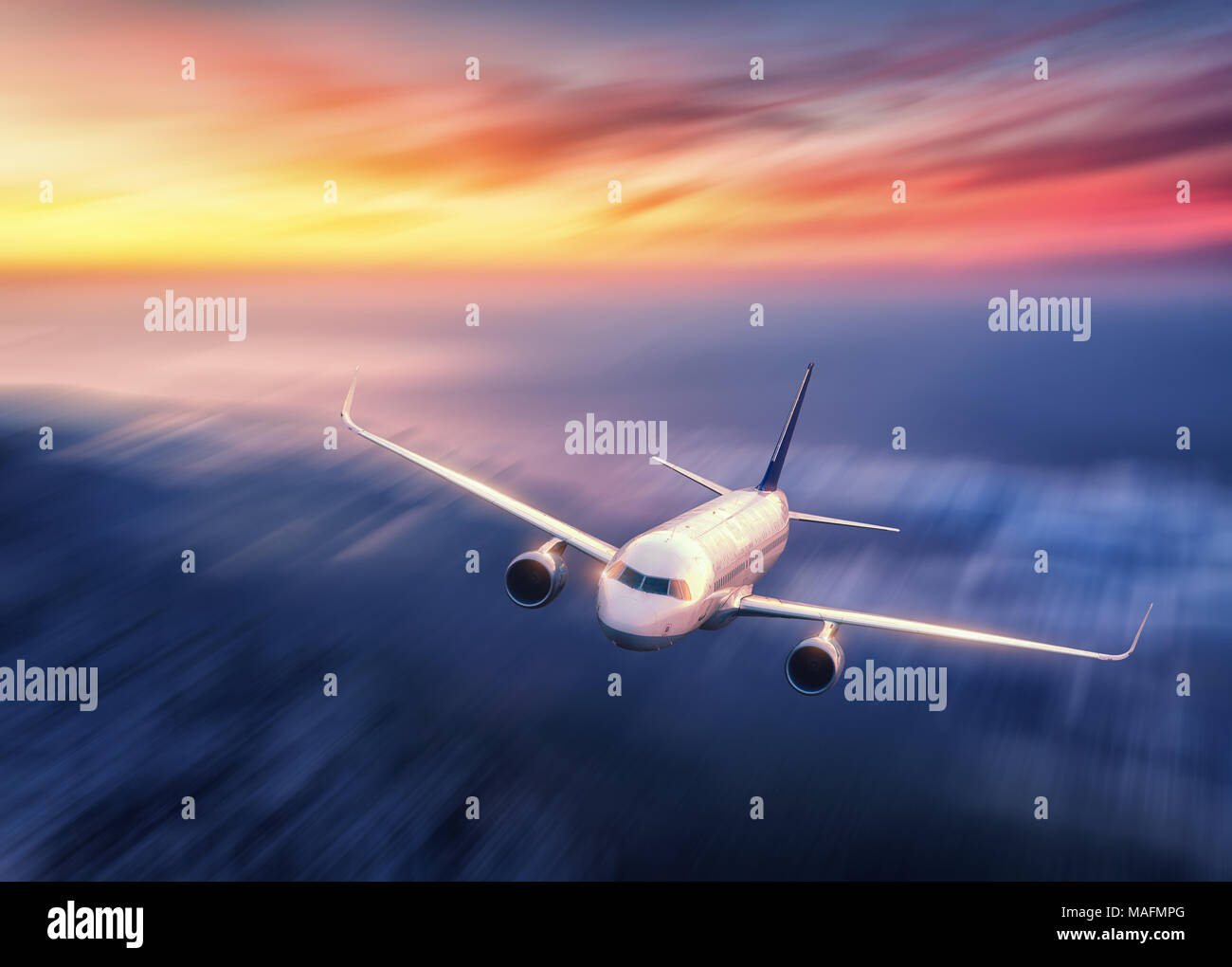 Modern airplane with motion blur effect is flying over low clouds at ...