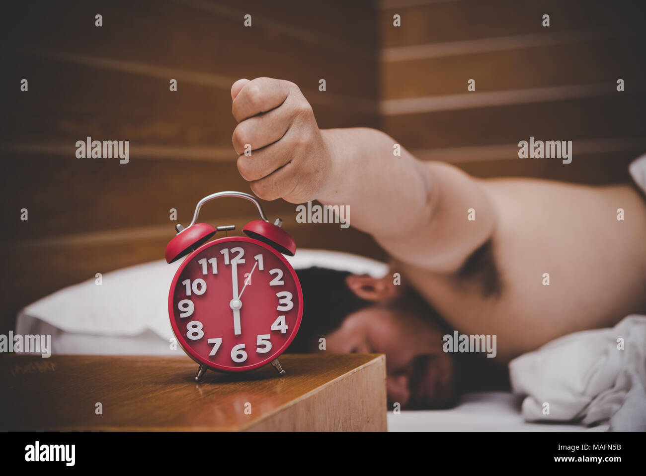Man being awakened by an alarm clock in his bedroom Stock Photo - Alamy