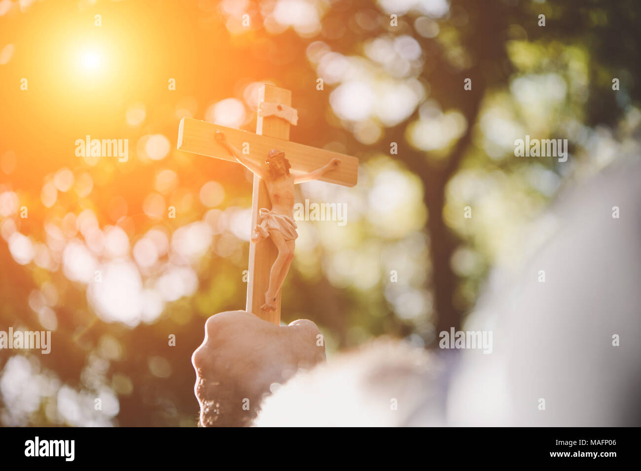 Male hands holding wooden jesus cross over into the sky with nature ...