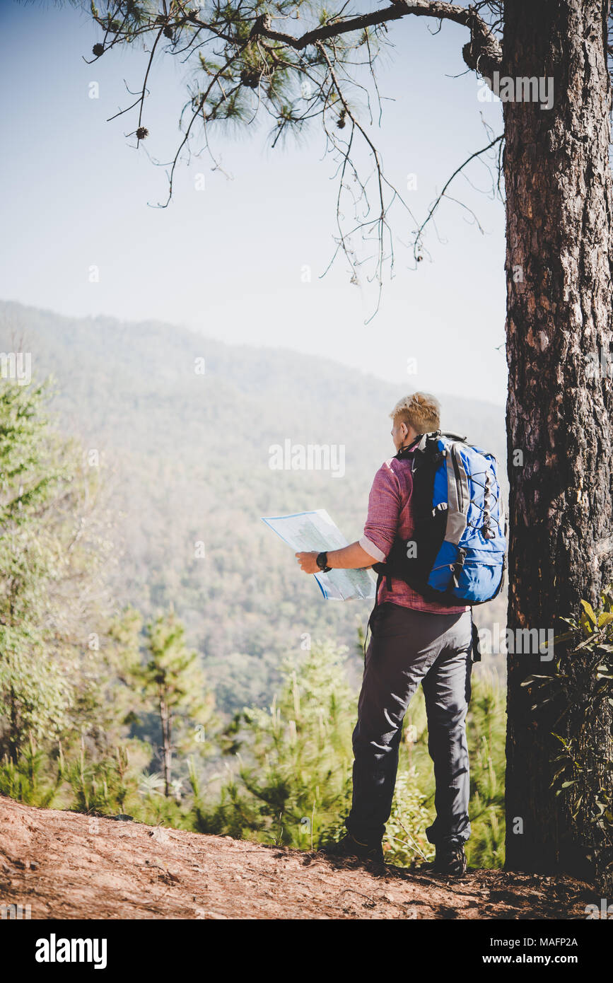 Hiker with map and big traveling backpack traveling to the mountain ...