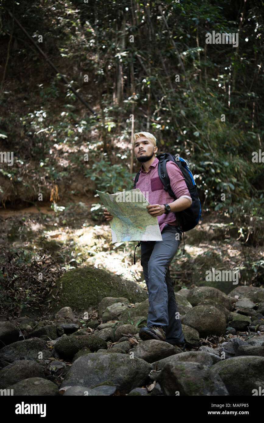 Adventure man observing map on a mountain path to find the the right ...
