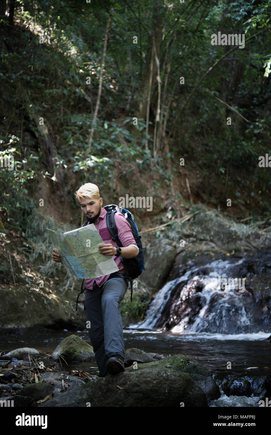 Adventure man observing map on a mountain path to find the the right ...
