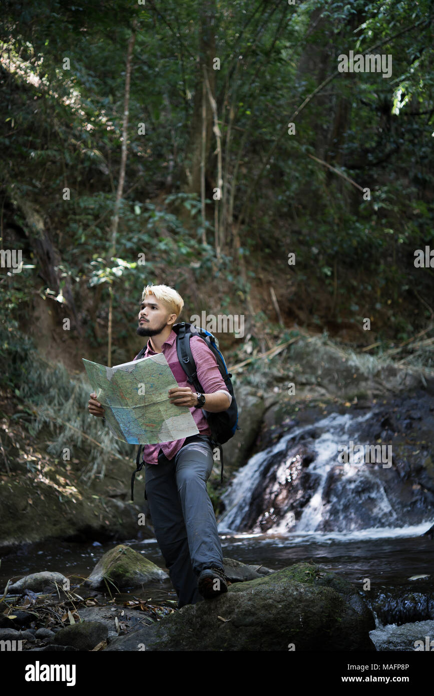Adventure man observing map on a mountain path to find the the right ...