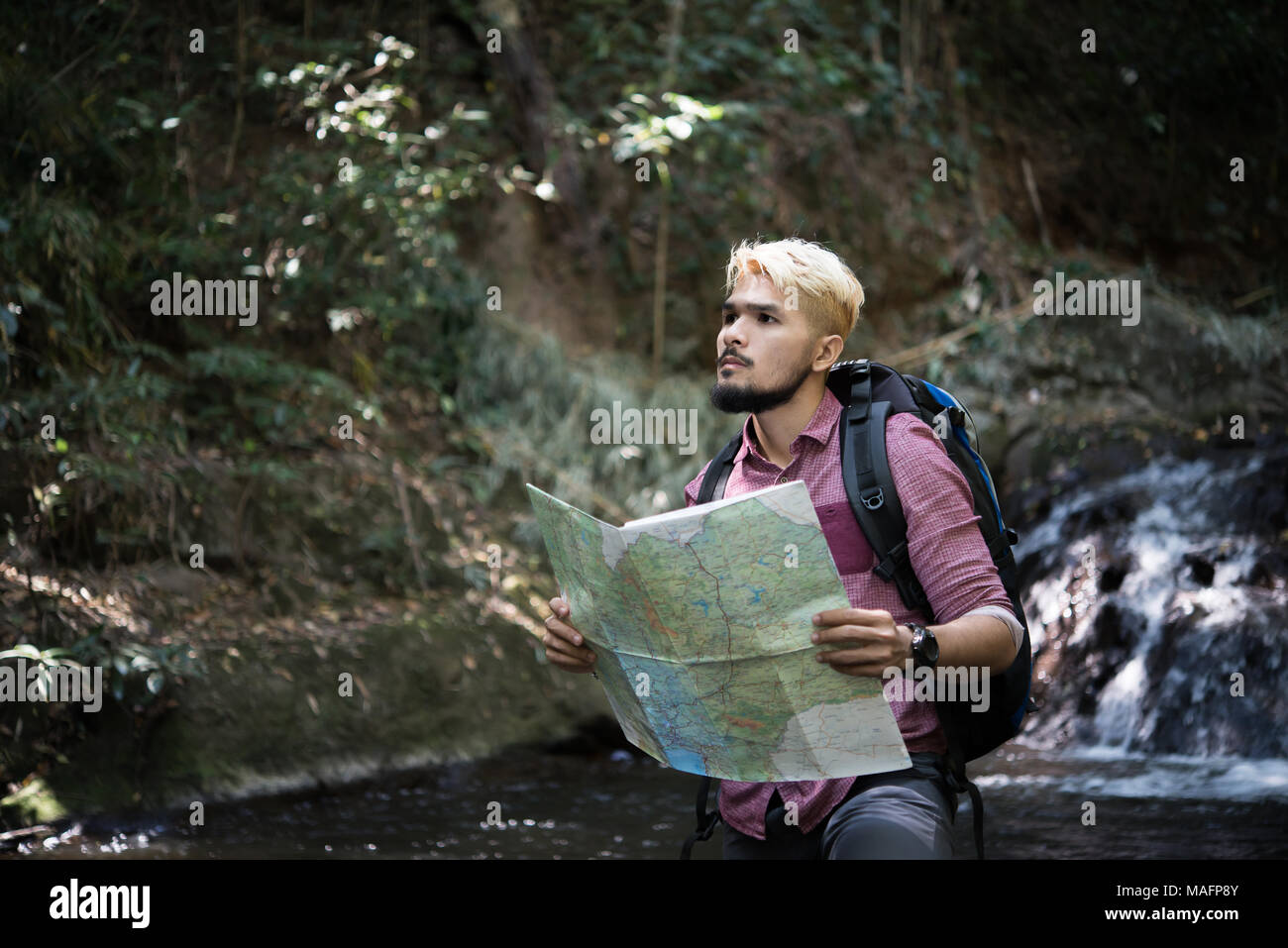Adventure man observing map on a mountain path to find the the right ...