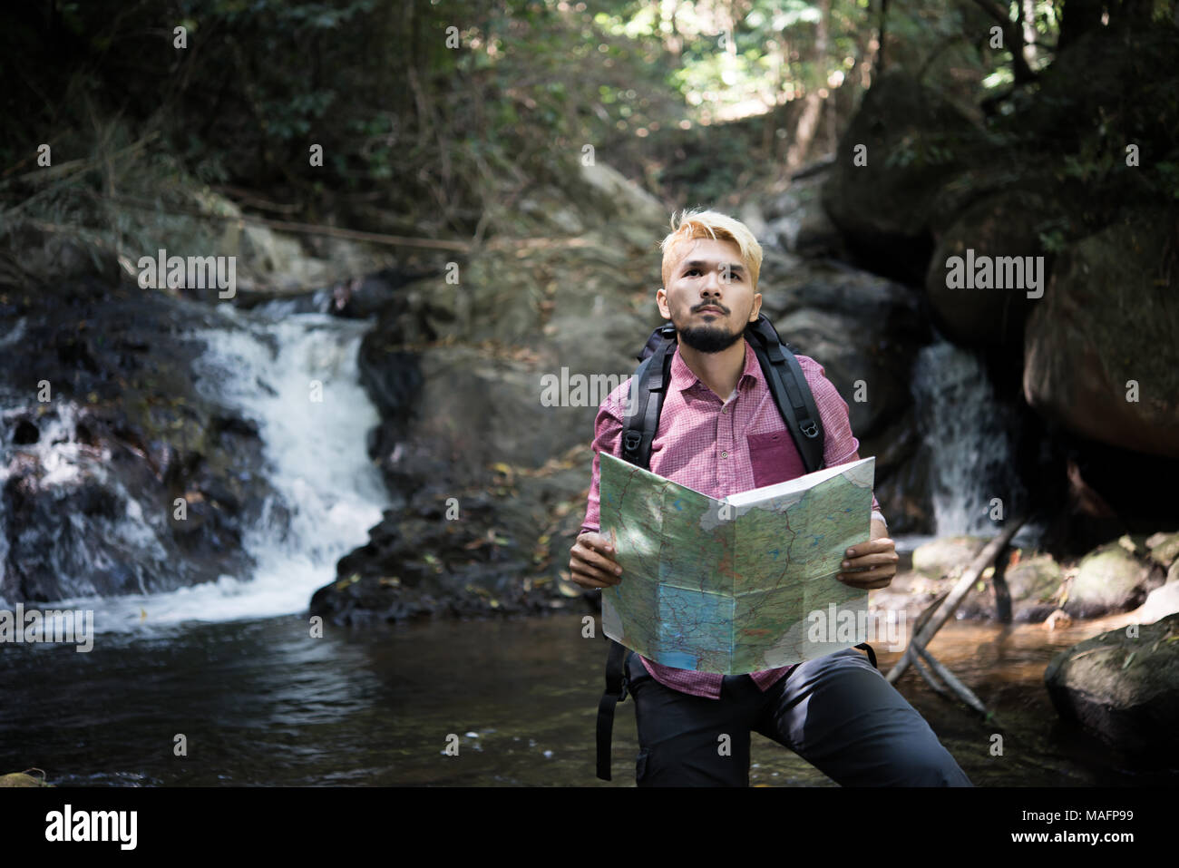 Adventure man observing map on a mountain path to find the the right ...