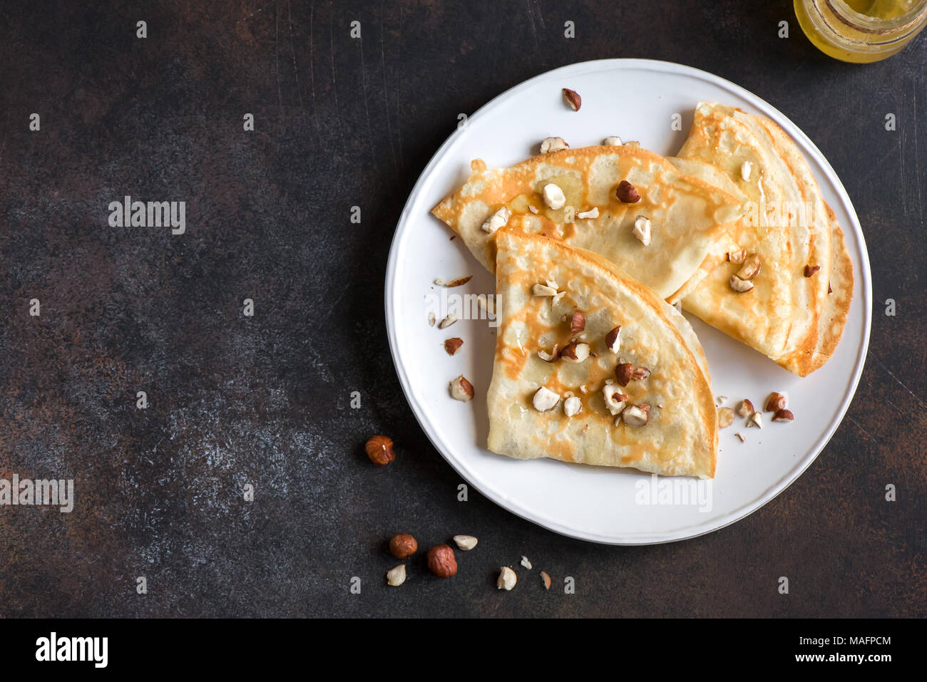 Crepes Suzette with honey and nuts on white plate over dark background ...