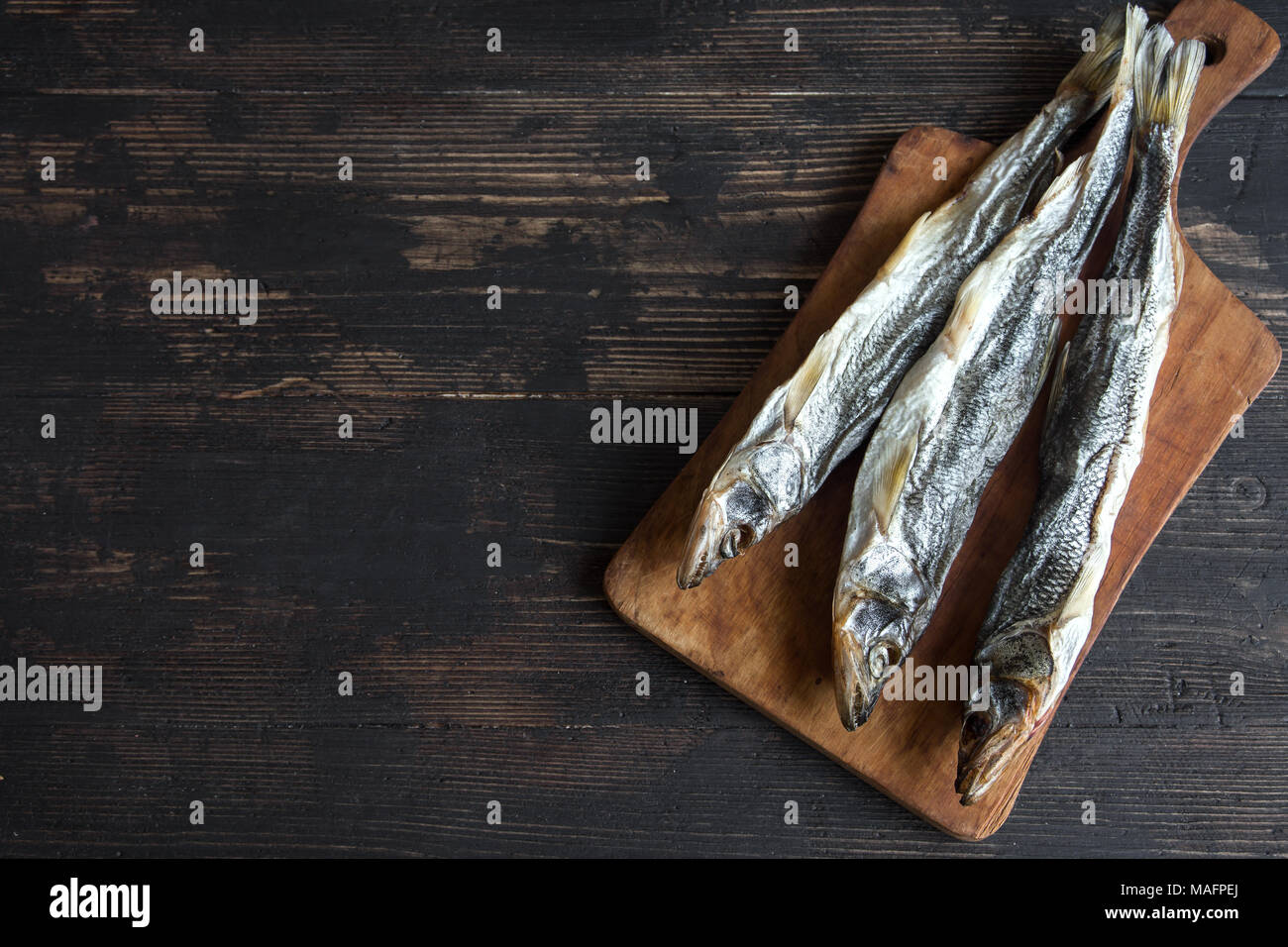 Sun dried fish, salted smelts over wooden background, top view, copy ...