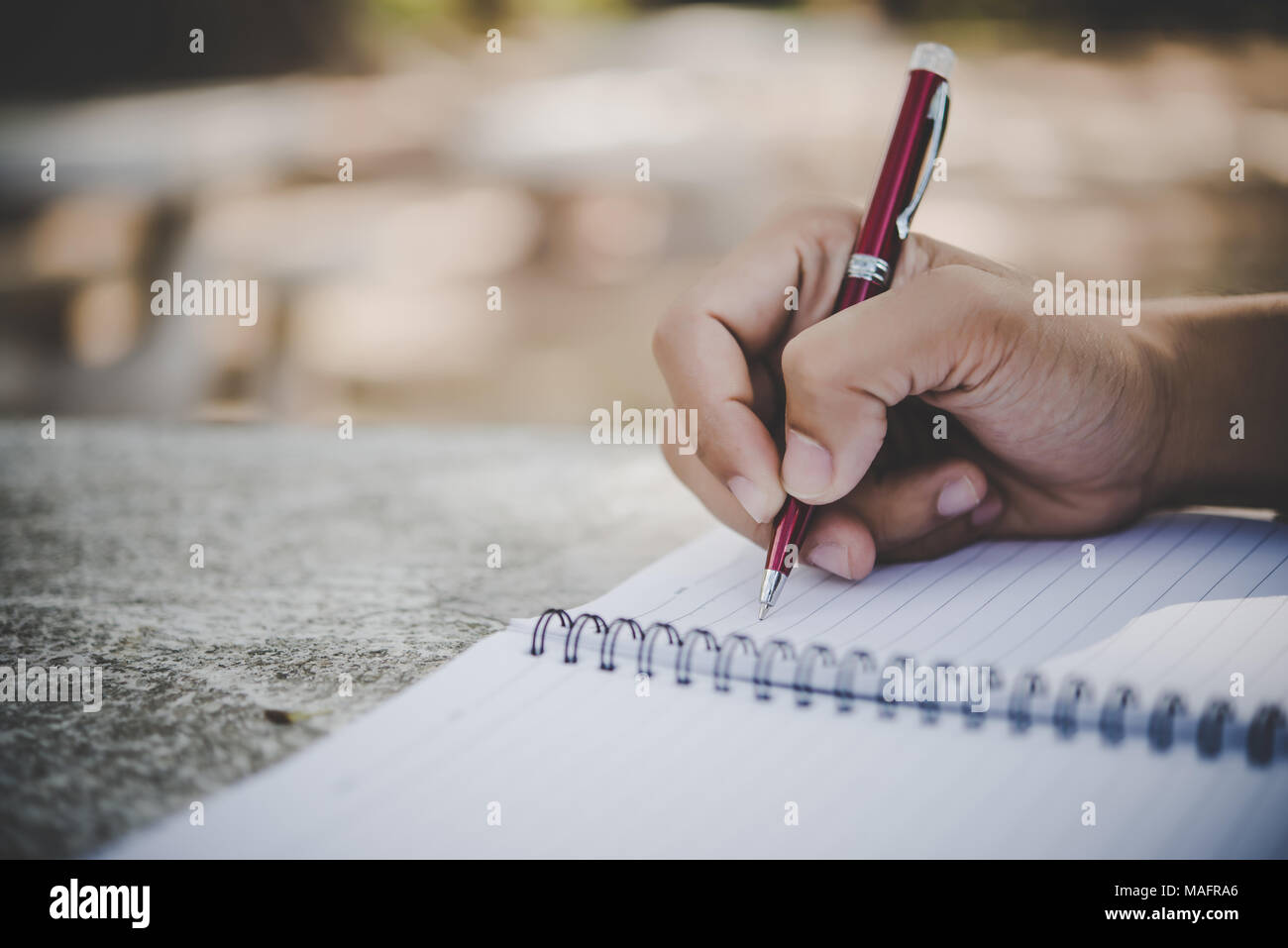 Man hand writing on his notebook Stock Photo - Alamy