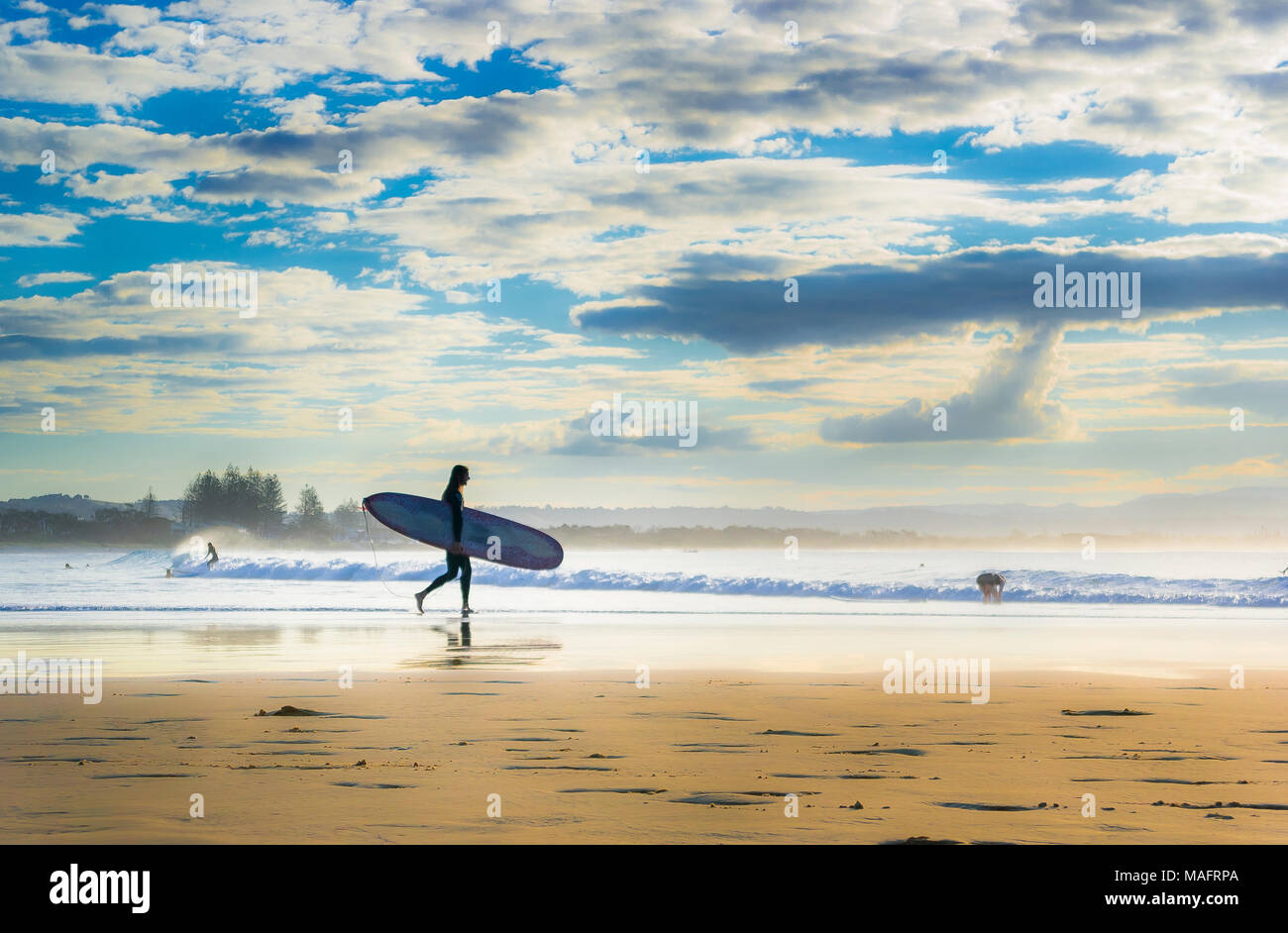 Surfer entering the surf at The Pass, Byron Bay, New South Wales ...