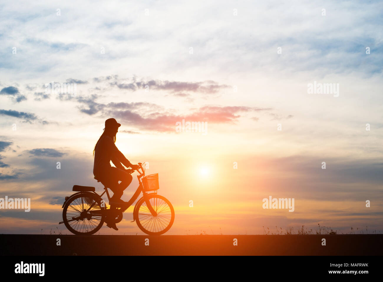 Young man ride bicycle on sunset background Stock Photo - Alamy