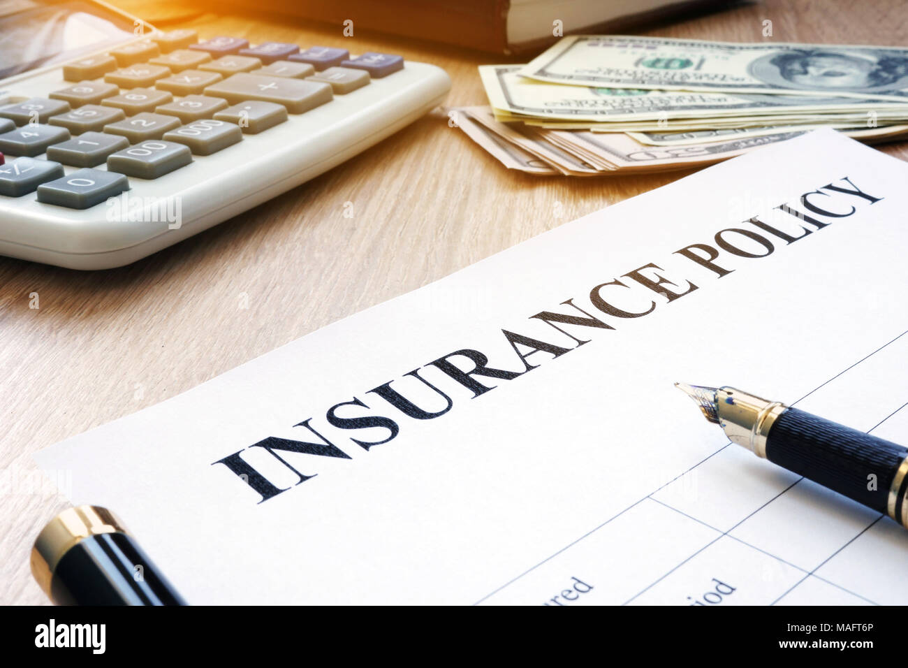 Insurance policy and dollar bills on an office desk Stock Photo - Alamy