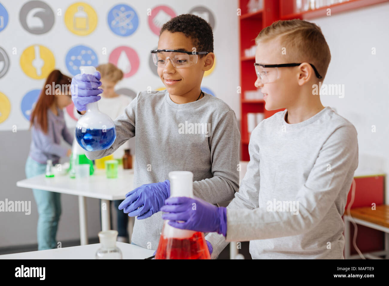 Upbeat students holding flasks with fuming substances Stock Photo - Alamy