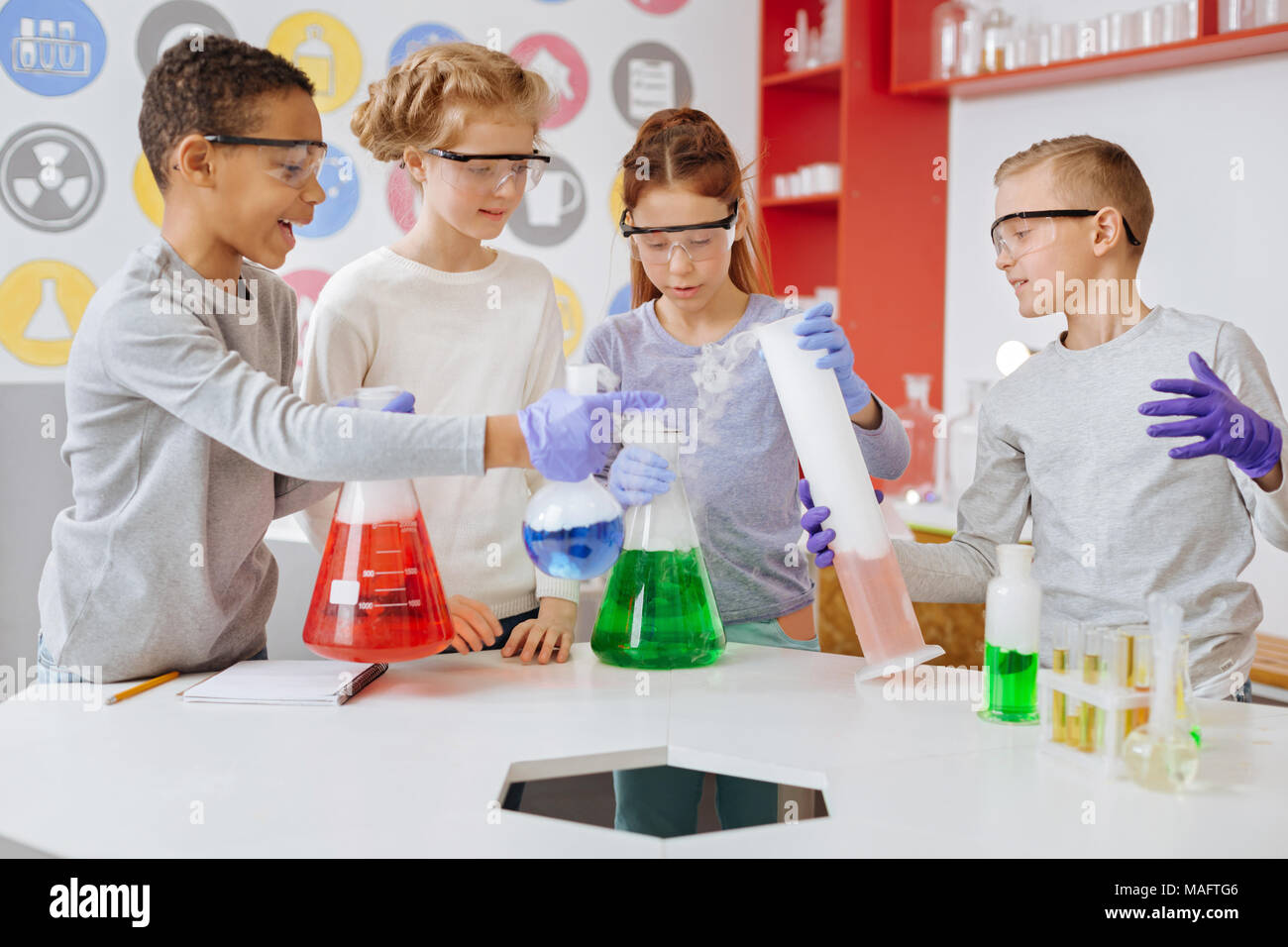 Group of students observing reactions in chemical glassware Stock Photo ...