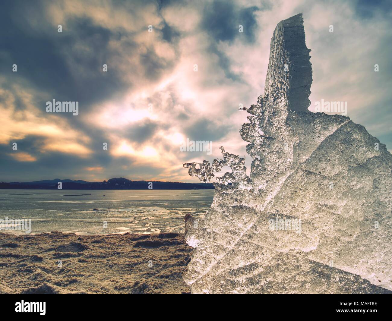 Icy sheets melting on sandy beach. End of long and crue winter coming ...