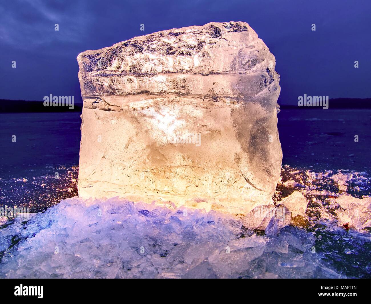 Blue ice cubes shine on flat glacier surface. Thanks to spot light ...