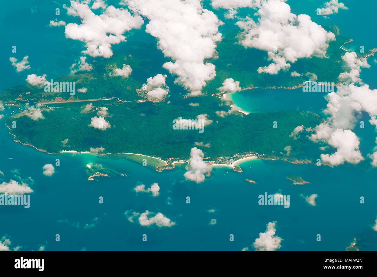 Aerial top view through clouds to large island in the ocean. Vacation ...
