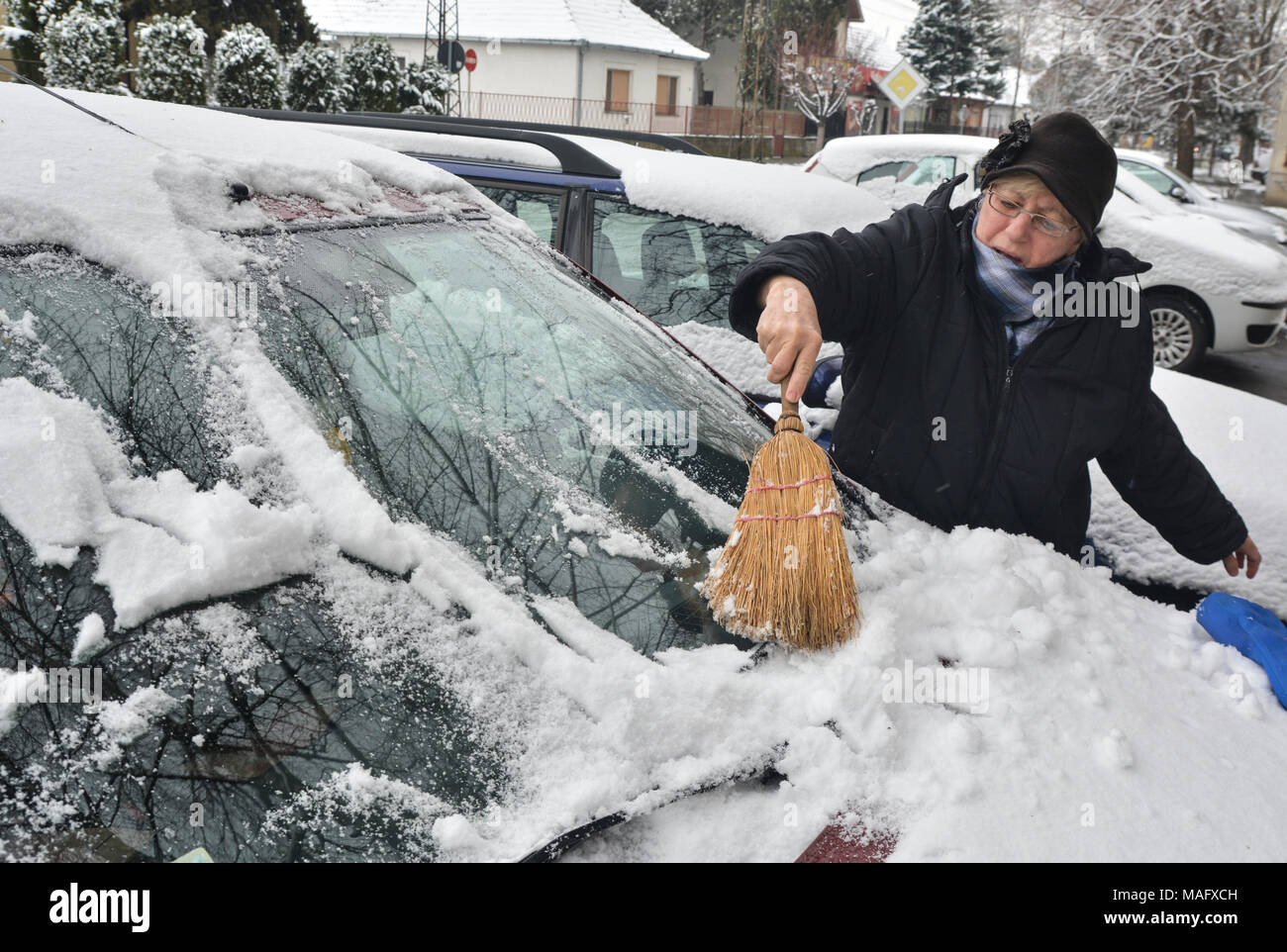 Woman driver cleans the snow from the car by hand and brush Stock Photo ...