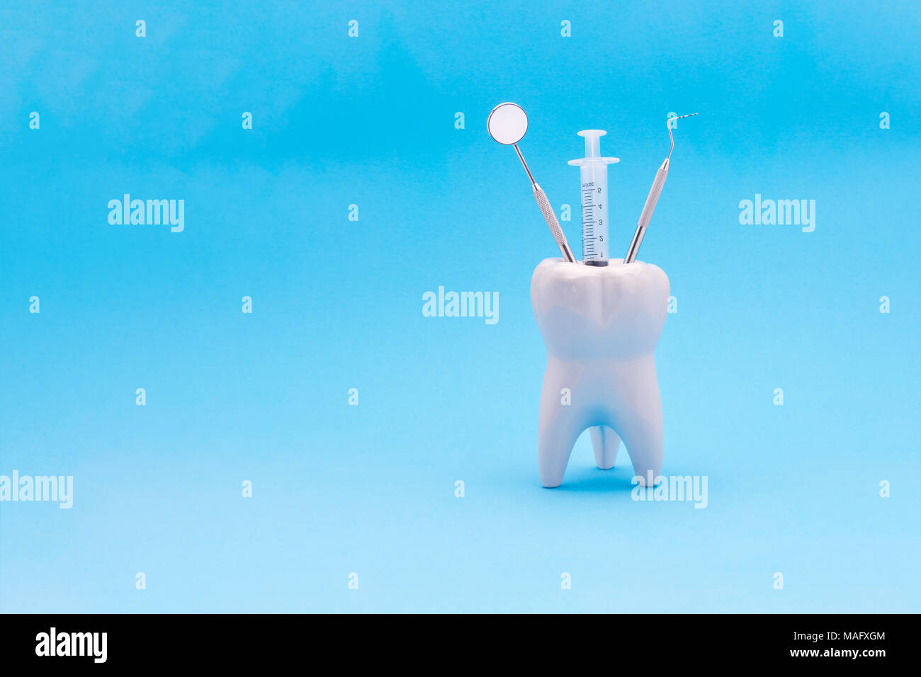 dental instruments mirror a probe a tweezers syringe stand in a ceramic ...