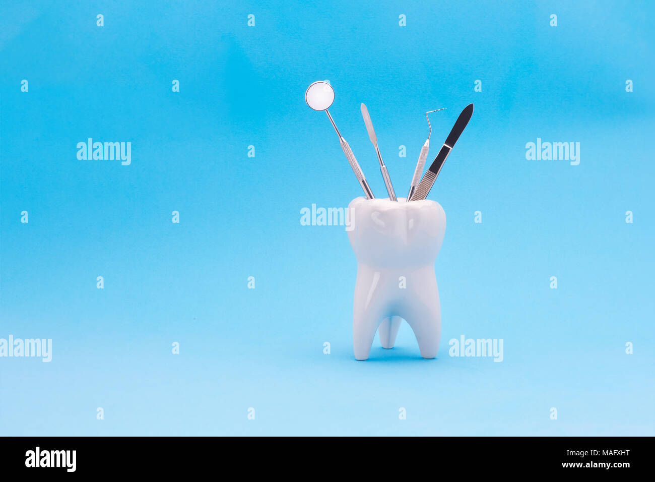 dental instruments mirror a probe a tweezers syringe stand in a ceramic ...