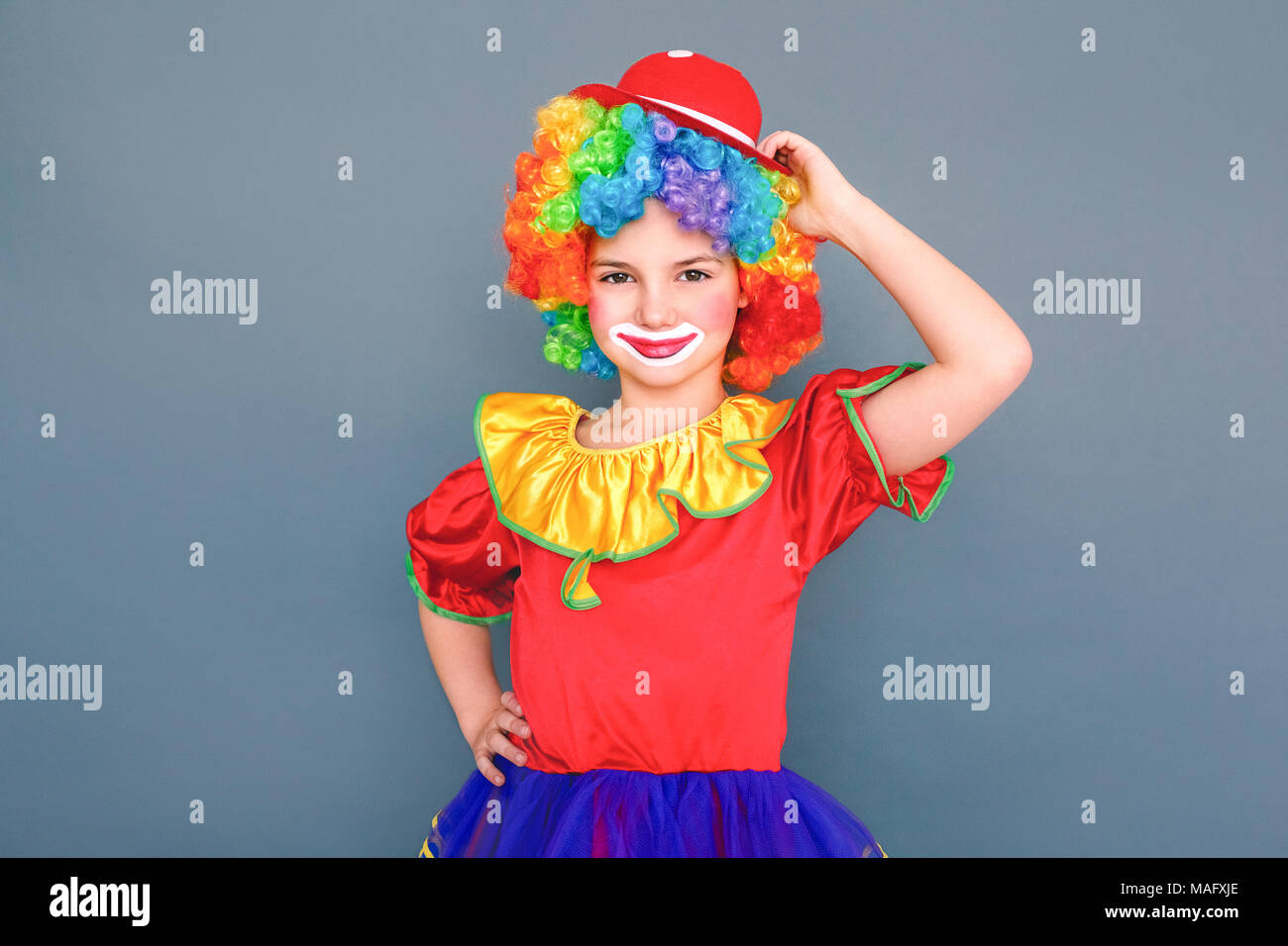 Cute clown girl holding her hat and toothy smiling. Studio shot ...