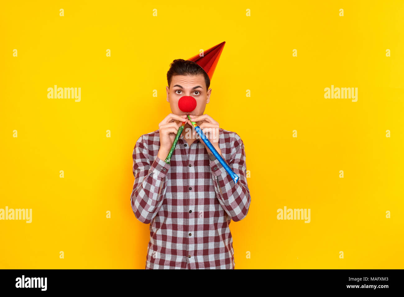 Humorous clown man holding two pipe and grimace at camera. Fool's day ...