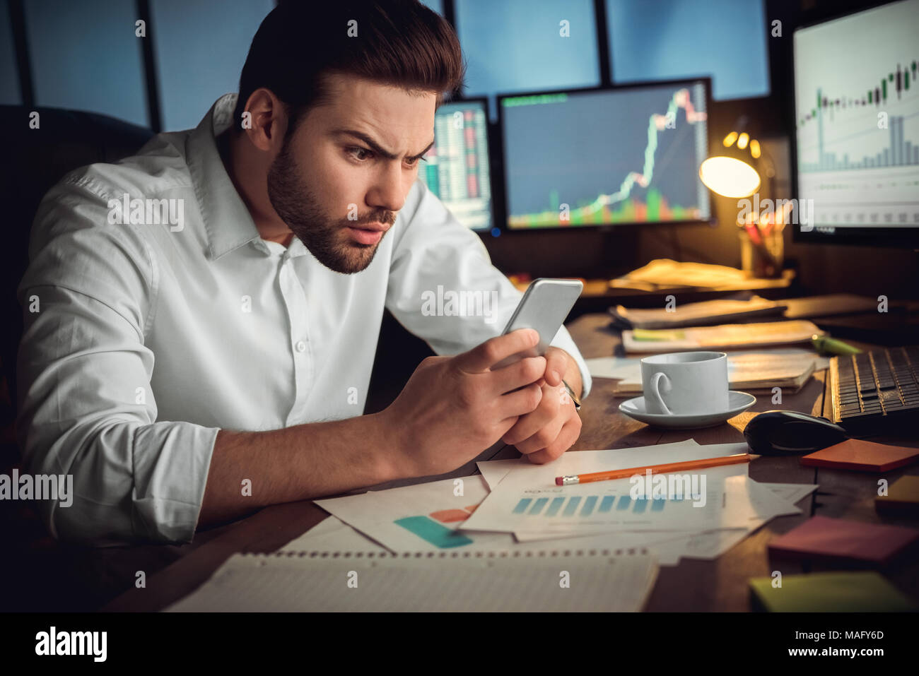 What Trader with shocked face look in screen smart phone. Indoor ...